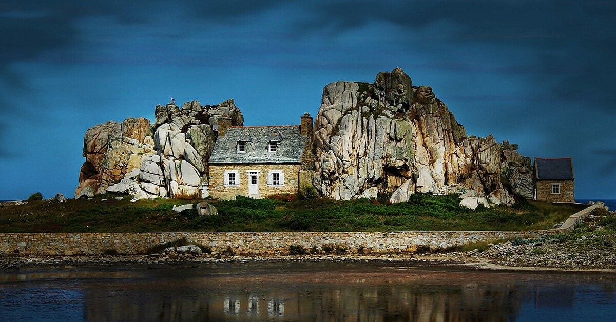 Strange house with its back to the sea, sandwiched between two giant rocks